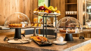 Buffet com diversas opções de comida, incluindo frutas, doces e um canto de café.
