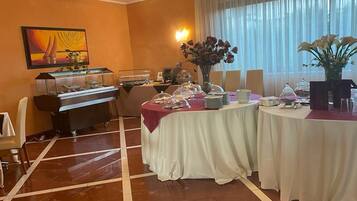 Uma sala de jantar com mesas postas para refeição, um buffet e um quadro na parede.