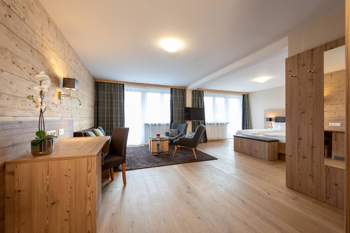 Uma sala de estar moderna com piso de madeira, um sofá, uma mesa de centro e uma televisão.