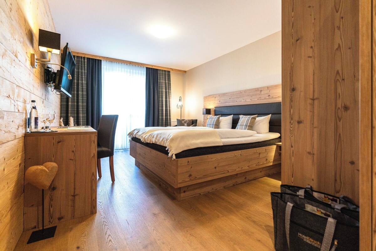 Um quarto com painéis de madeira, uma cama, uma escrivaninha e uma cadeira.