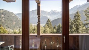 Varanda de madeira com vista para montanhas nevadas e floresta densa.