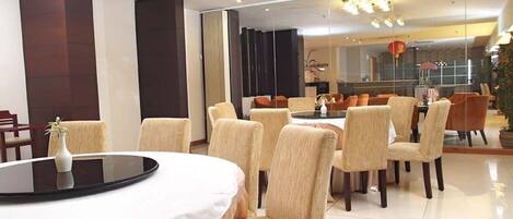 Uma sala de jantar moderna com uma mesa redonda e cadeiras bege estofadas.