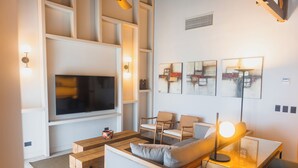 Uma sala de estar moderna com televisão de tela plana, assentos confortáveis, obras de arte na parede e estantes embutidas.