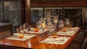 Mesa de jantar posta com taças de vinho, velas e uma garrafa de vinho.