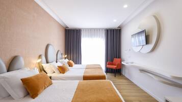 Quarto de hotel com duas camas, uma televisão na parede, uma escrivaninha e uma cadeira.