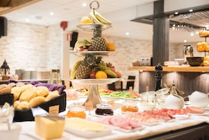 Buffet com diversos alimentos, incluindo frutas, queijos e carnes.