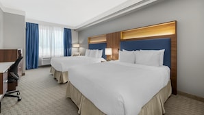 Quarto de hotel com duas camas, uma escrivaninha e uma cadeira.