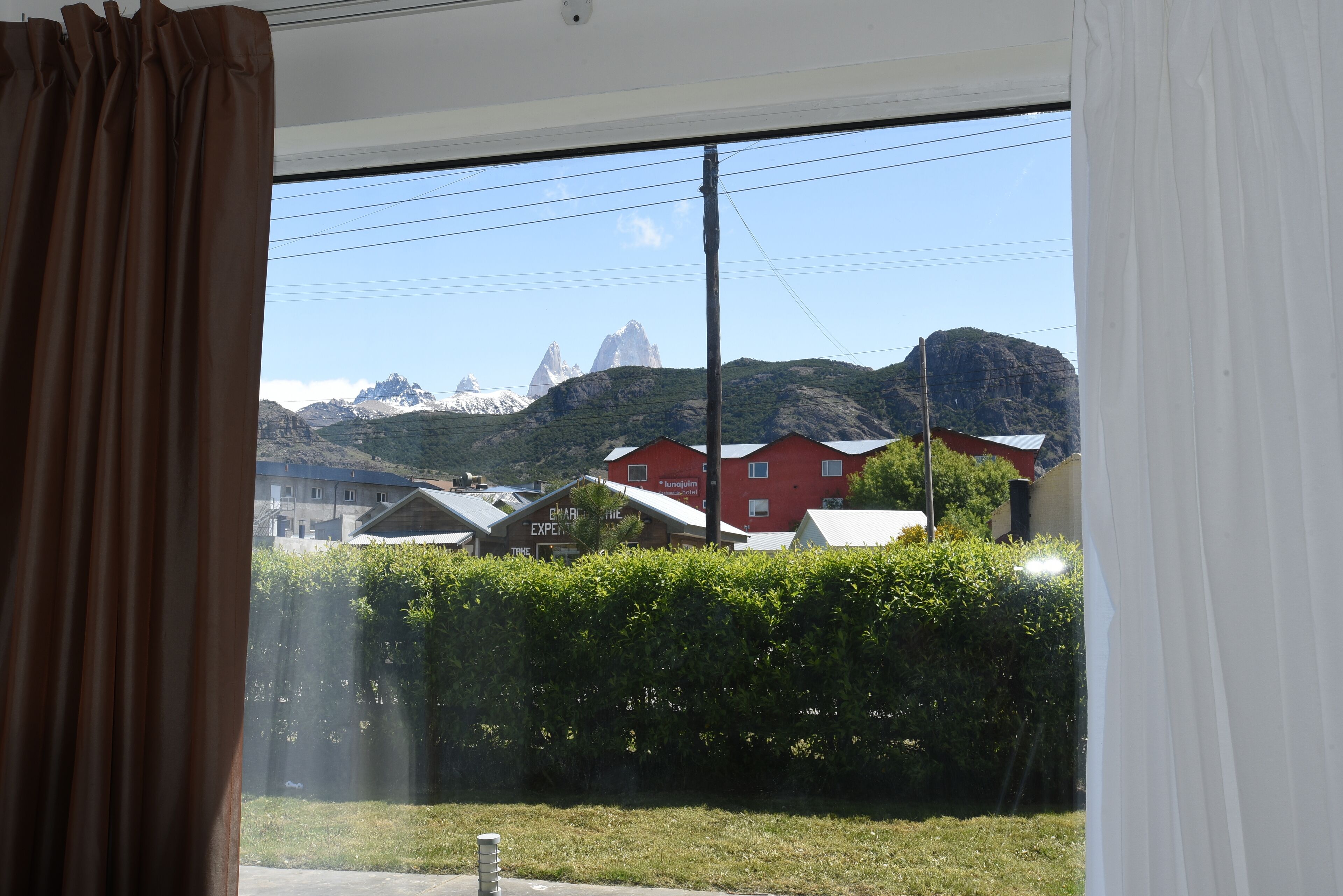 Vista pela janela de uma paisagem montanhosa com edifícios ao fundo.