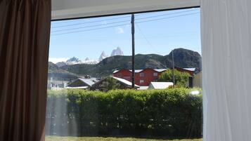 Vista pela janela de uma paisagem montanhosa com edifícios ao fundo.