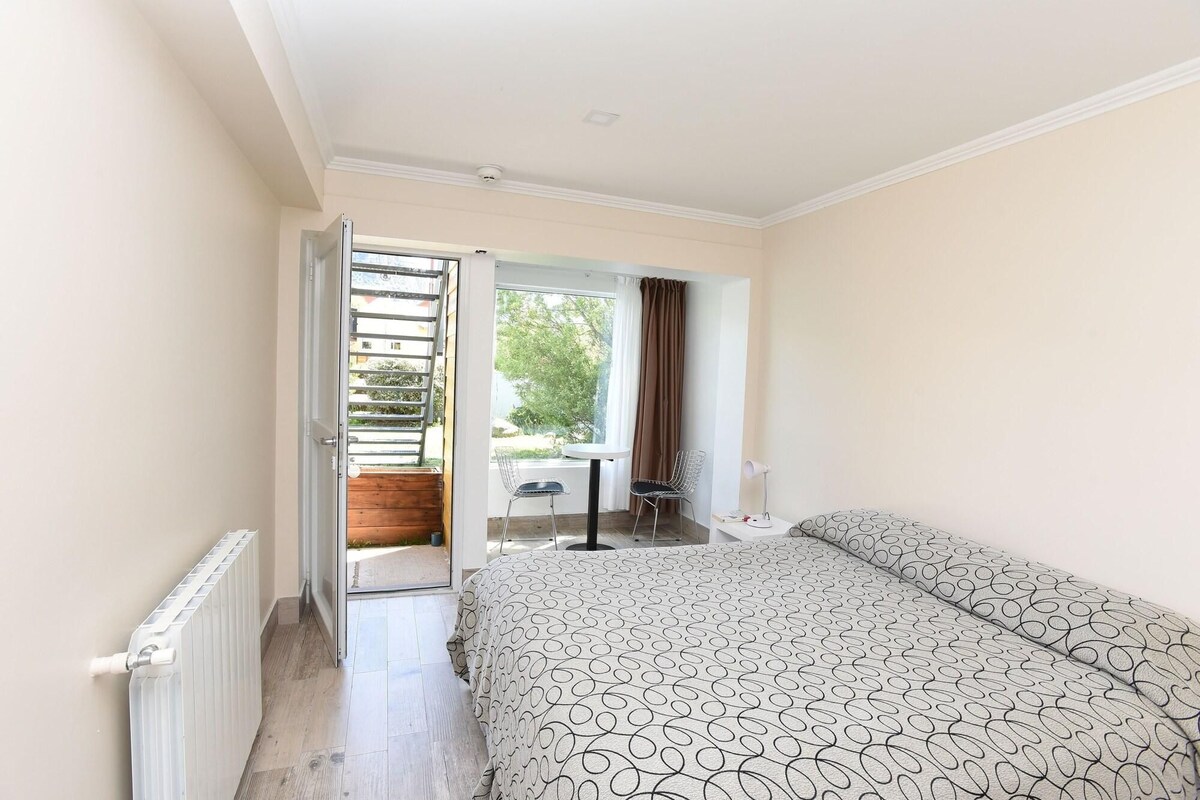 Quarto com cama, cadeira, escrivaninha e janela.