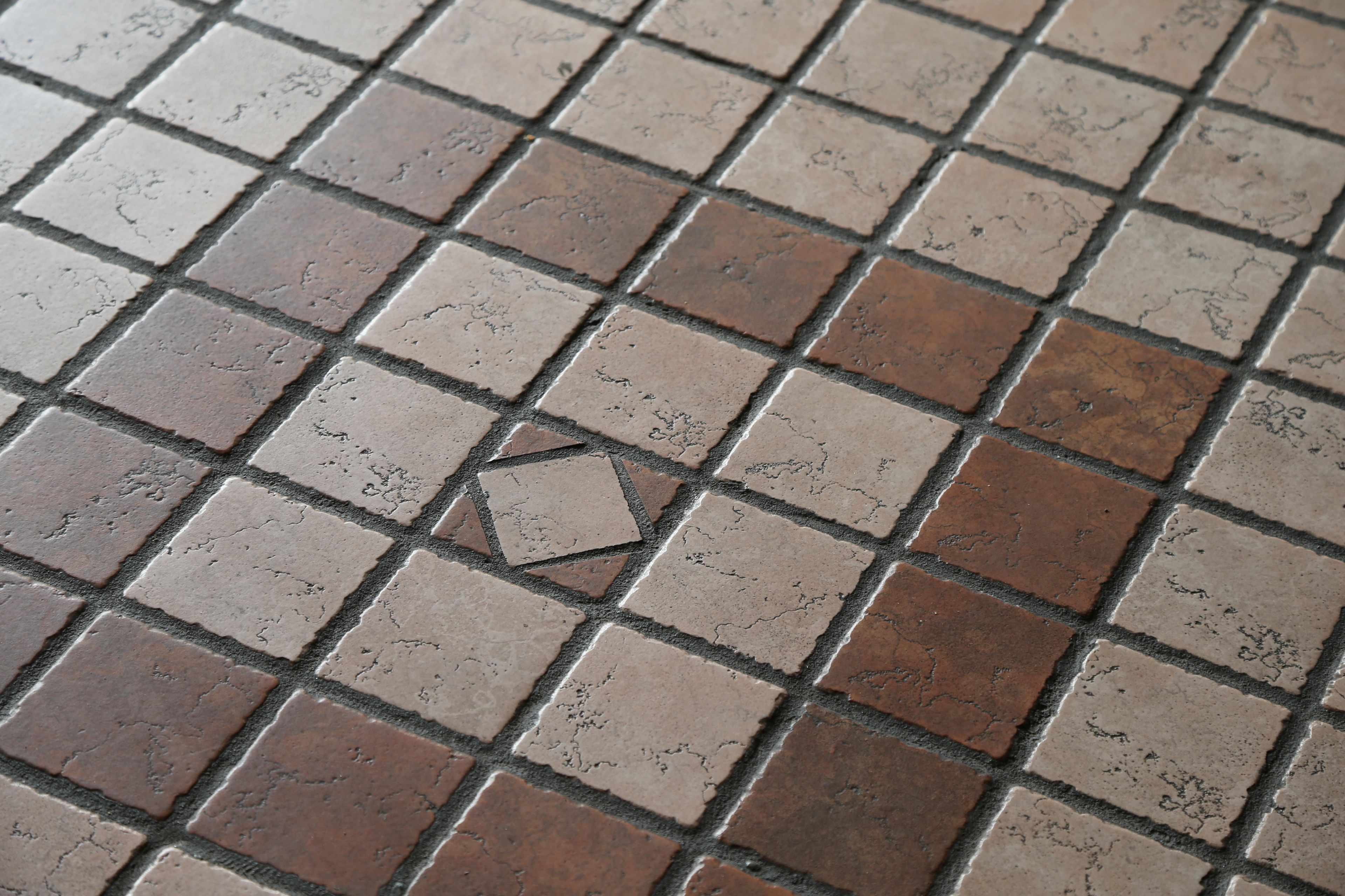 Um close-up de um chão de azulejos com um padrão de azulejos quadrados em tons de castanho e bege.