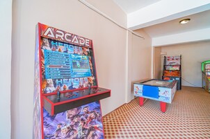 Um corredor com jogos de fliperama, incluindo uma máquina de Pac-Man, e uma mesa de bilhar.
