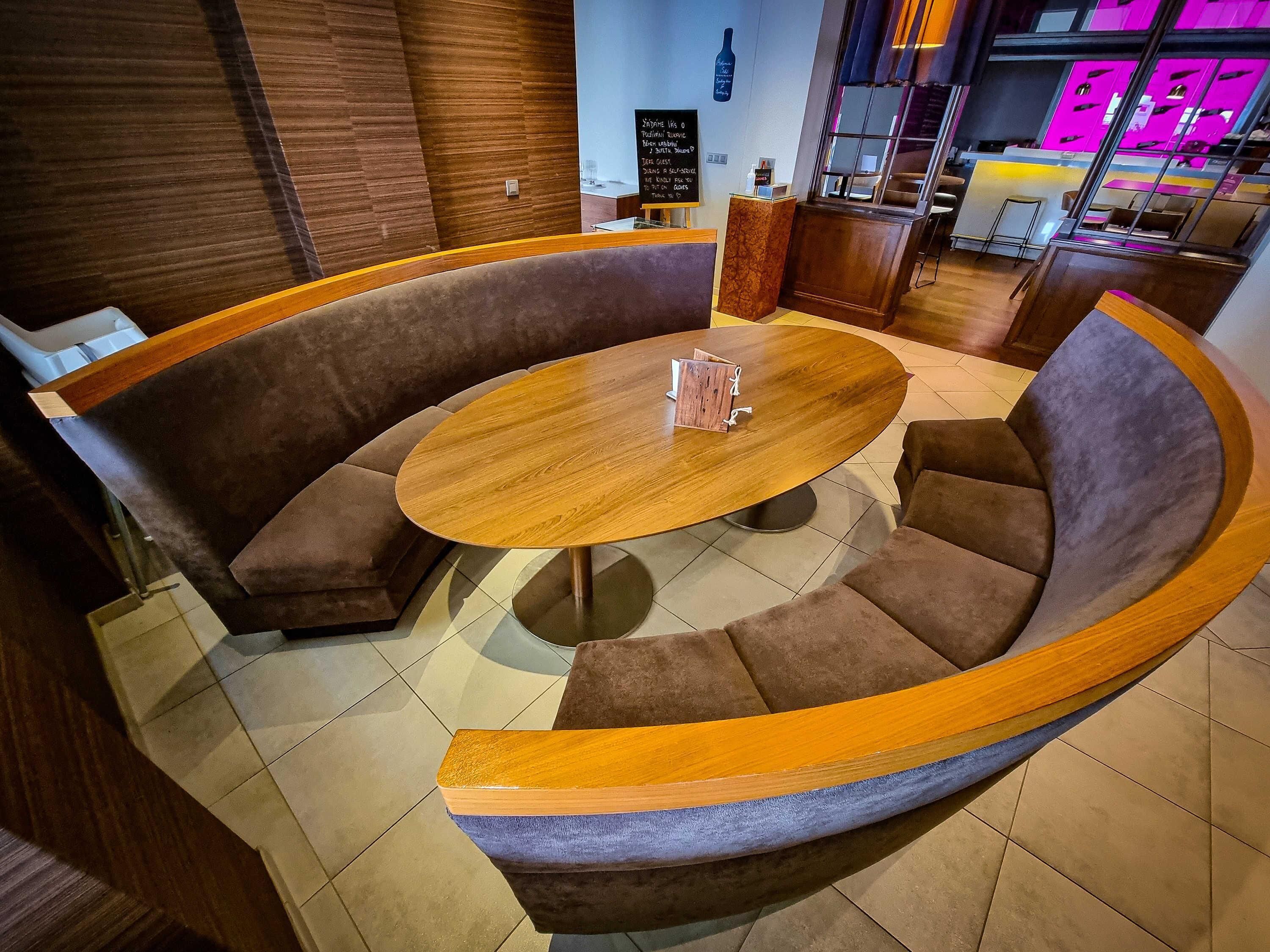Uma área de estar circular com mesa de madeira e cadeiras estofadas.
