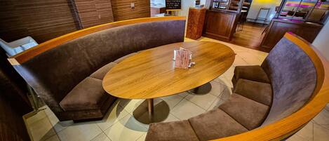 Uma área de estar circular com mesa de madeira e cadeiras estofadas.