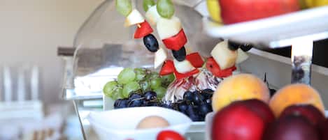 Buffet com diversas frutas e legumes, incluindo uvas, tomates e maçãs.