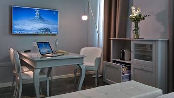 Quarto de hotel moderno com escrivaninha, cadeira, laptop e cama.