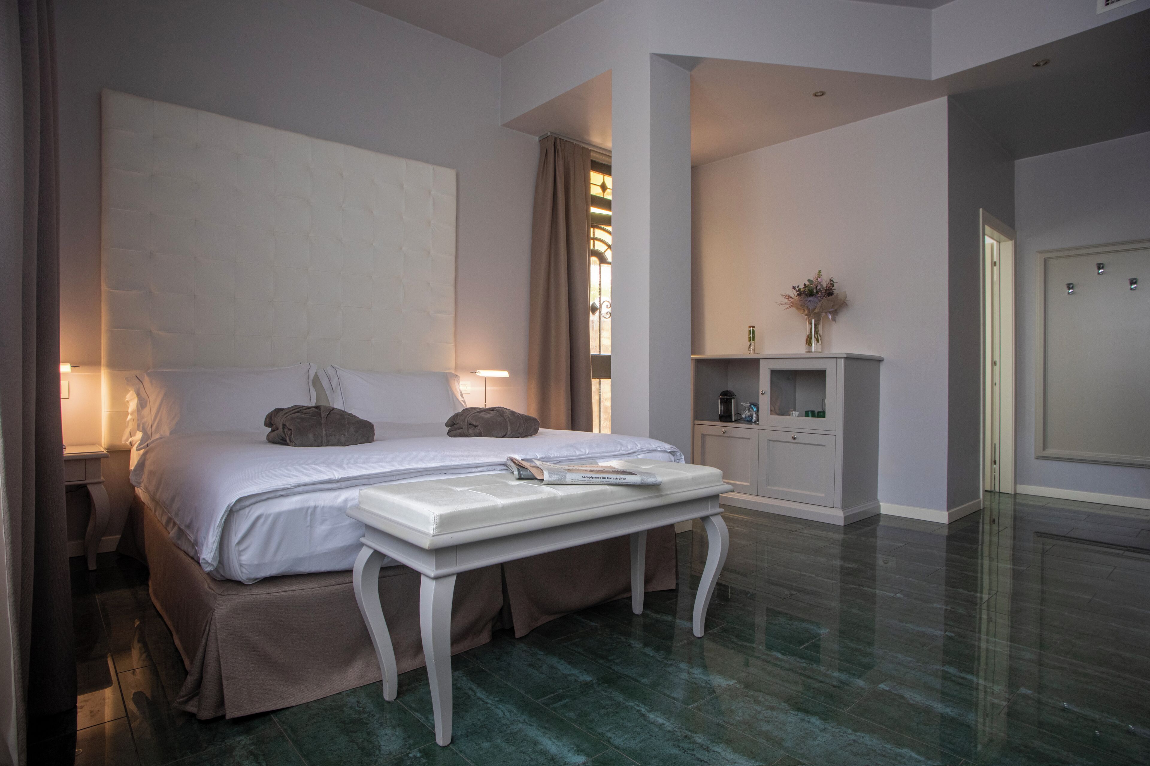 Quarto de hotel moderno com uma cama grande, uma mesa de cabeceira, um criado-mudo e um espelho.