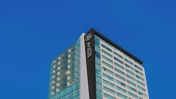 Um edifício de hotel alto com fachada moderna em vidro, entrada imponente e área circundante bem cuidada.