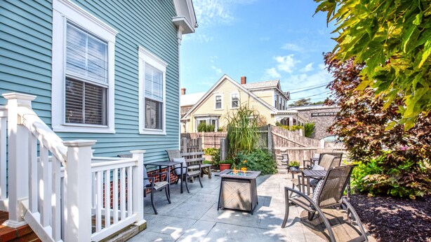 Um pátio com móveis externos, uma lareira e vista para as casas vizinhas.