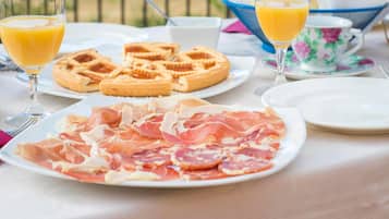 Uma mesa de café da manhã com waffles, presunto e suco de laranja.