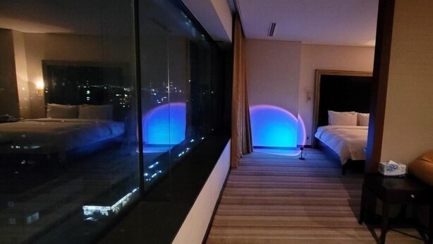 Quarto de hotel com uma janela grande, uma cama, um sofá e um quadro na parede.