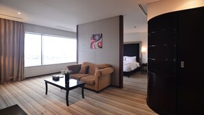 Quarto de hotel com sofá, mesa de centro, cama e um armário preto grande.