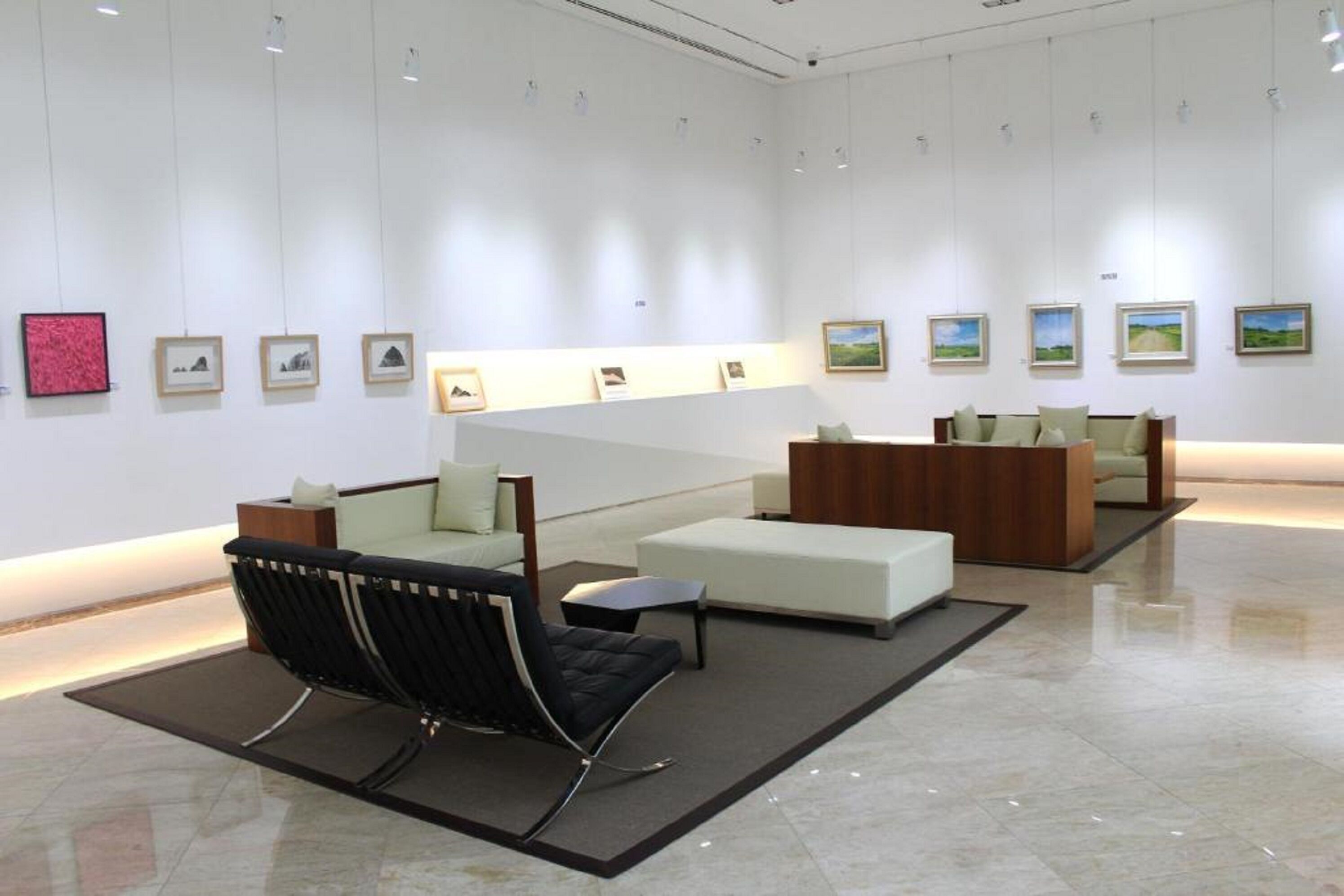 Uma galeria de arte moderna com mobiliário contemporâneo, incluindo um sofá, uma cadeira e uma pequena mesa.