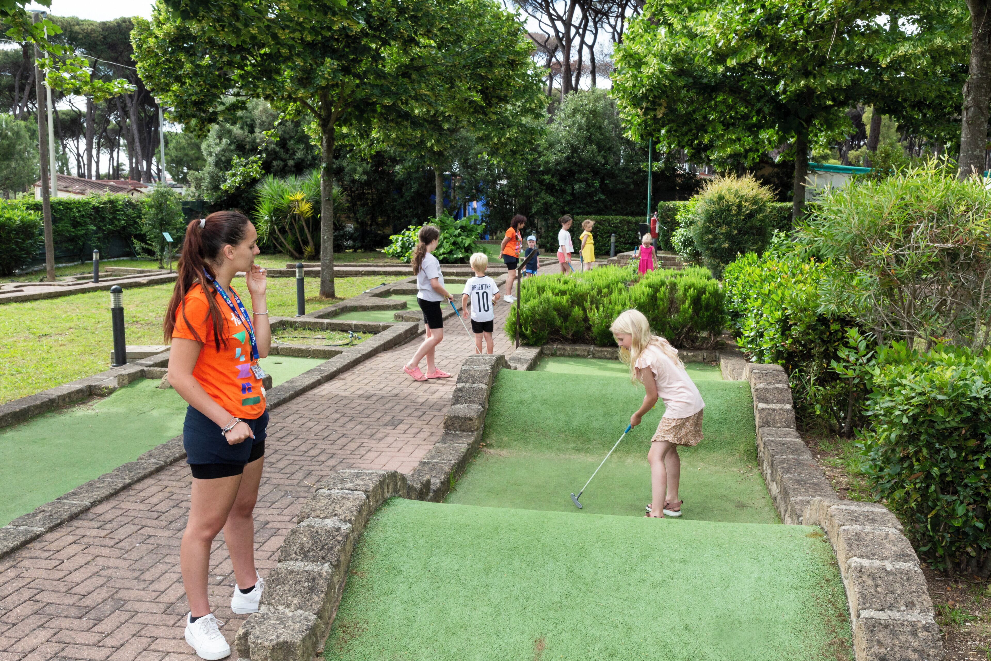 Um campo de mini golfe com caminho de tijolos e grama sintética verde.