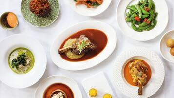 Diversos pratos em travessas brancas, incluindo frutos do mar, carne e legumes.