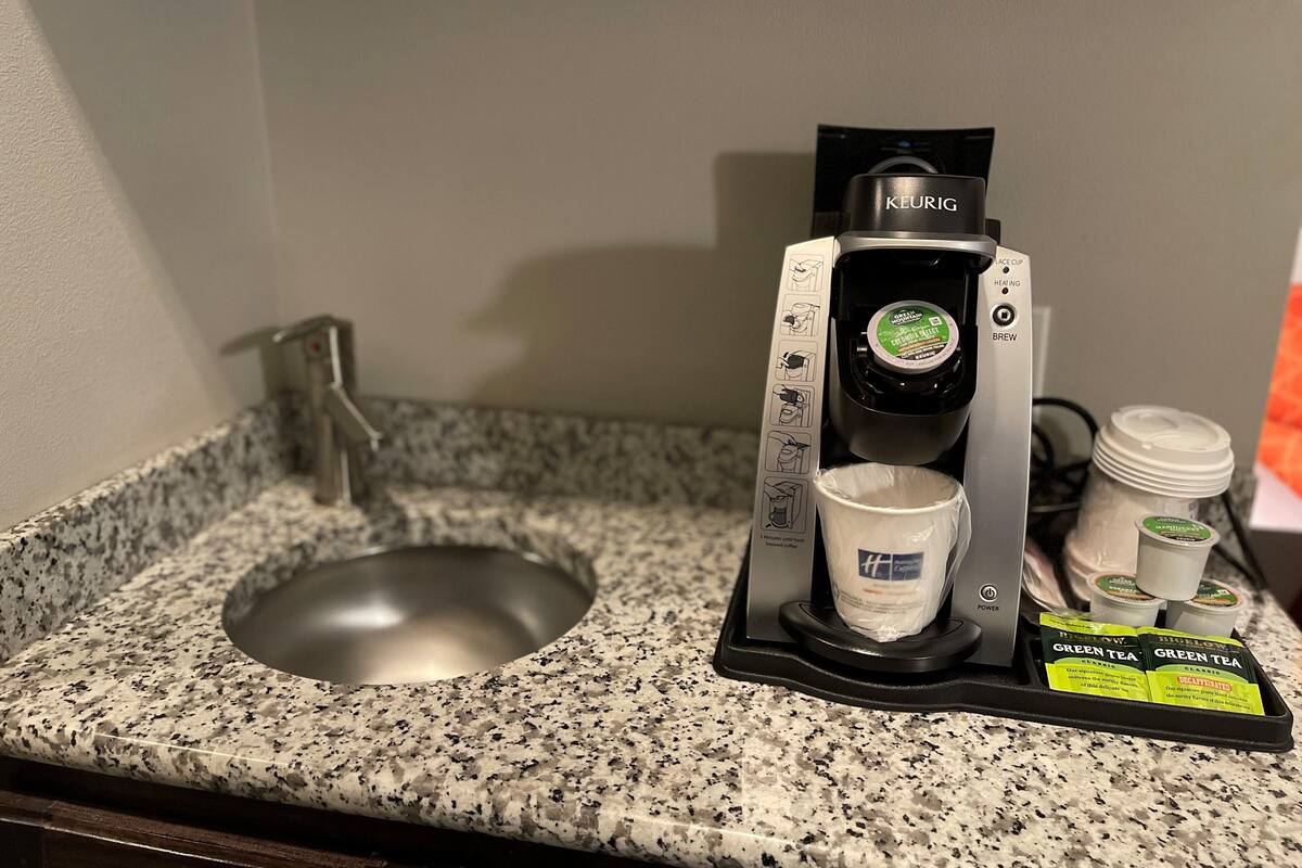 Máquina de café Keurig com bandeja coletora, pia e bancada.