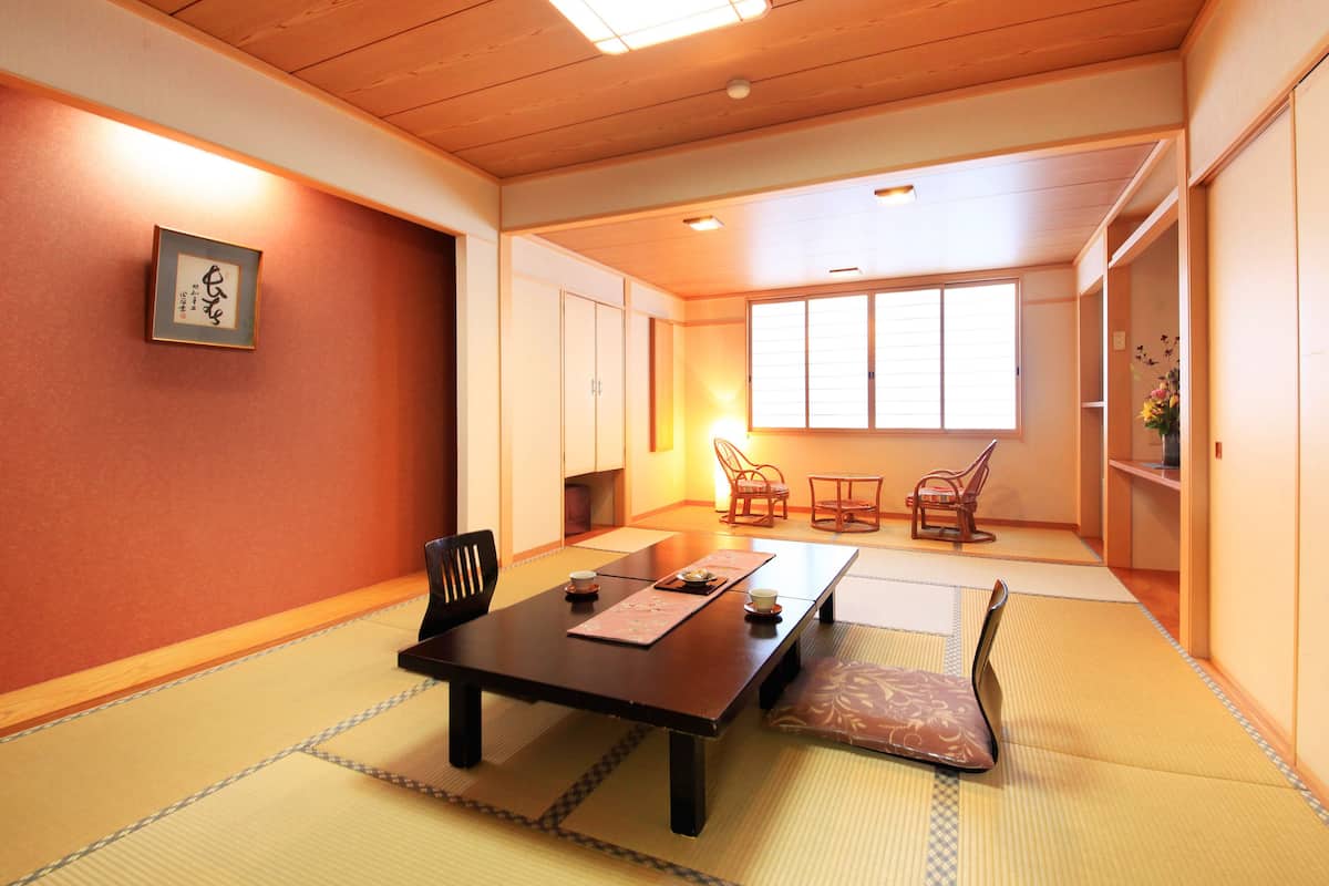 Um quarto japonês tradicional com tatames, uma mesa baixa e cadeiras.