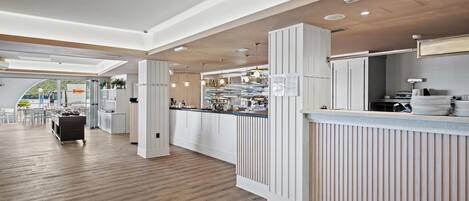 Cozinha moderna com piso de madeira, armários brancos e luminárias pendentes.