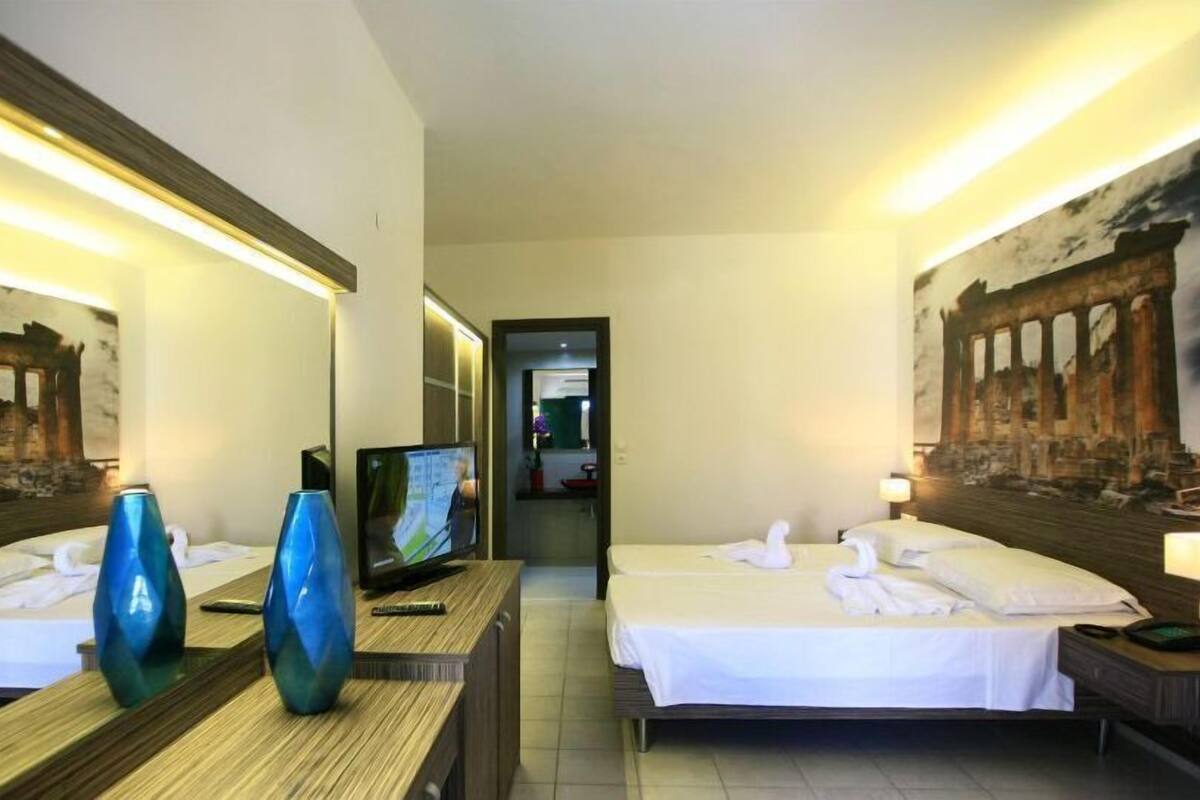 Quarto de hotel com duas camas, televisão e obras de arte retratando ruínas.