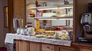 Disposição de buffet com diversos alimentos, uma máquina de café e um telefone.