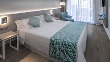 Quarto de hotel moderno com uma cama grande, mesas de cabeceira, um espaço para sentar e uma televisão.