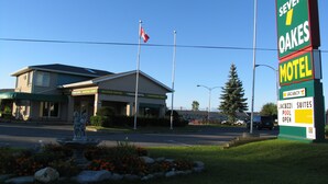Um motel com uma placa indicando 'Seven Oaks Motel' e um mastro com a bandeira do Canadá.