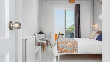 Quarto de hotel moderno com cama, escrivaninha e cadeira, varanda com vista e luminária pendente.