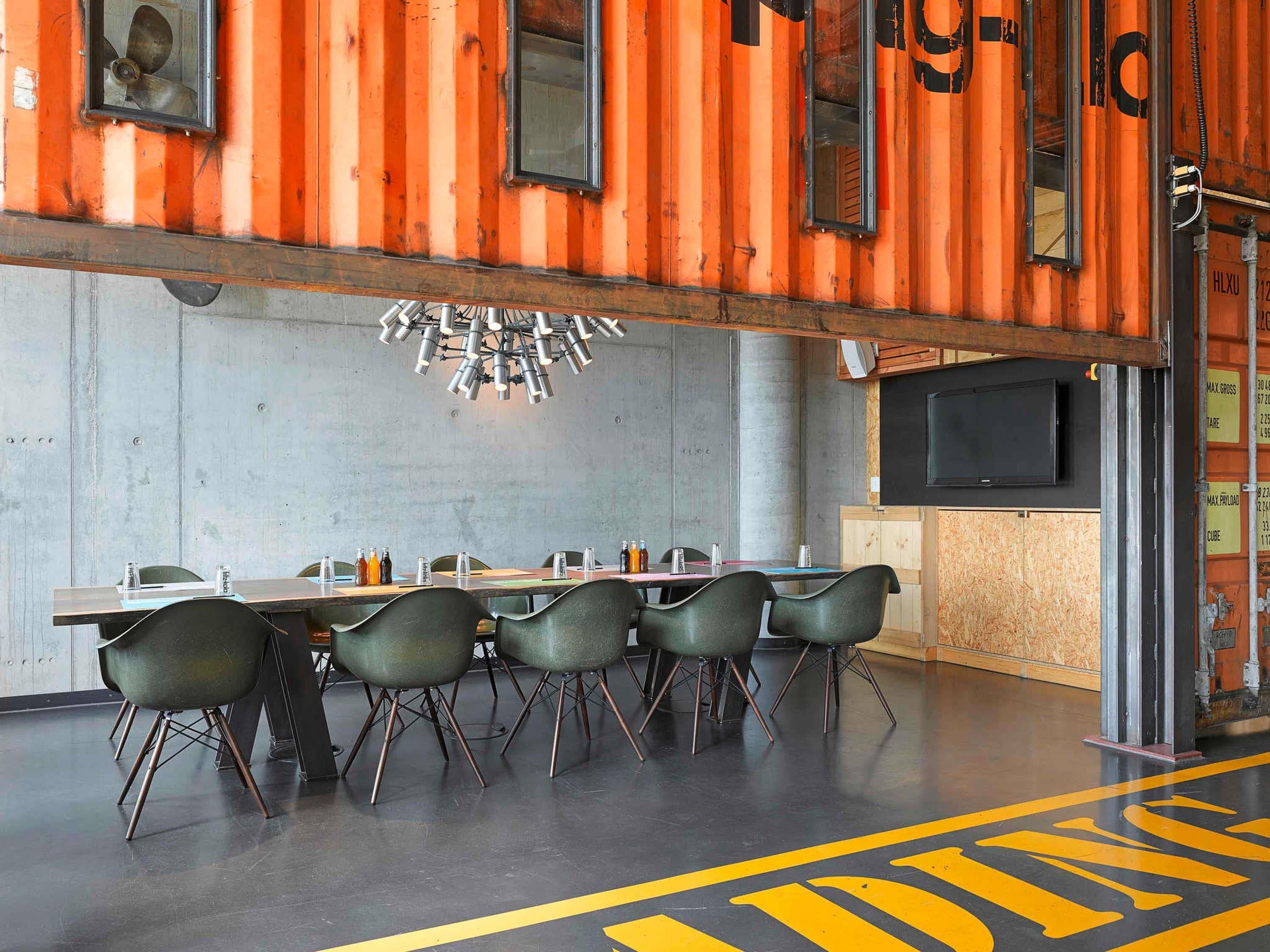 Uma área de jantar moderna com uma mesa comprida, várias cadeiras e um lustre de design exclusivo.