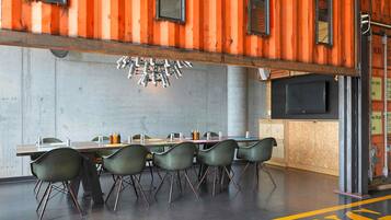 Uma área de jantar moderna com uma mesa comprida, várias cadeiras e um lustre de design exclusivo.