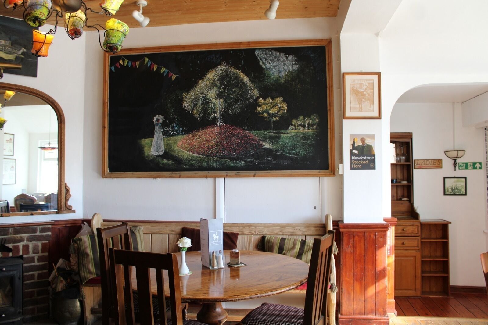 Uma sala de jantar com um quadro grande, mobiliário de madeira e uma lareira de tijolos.