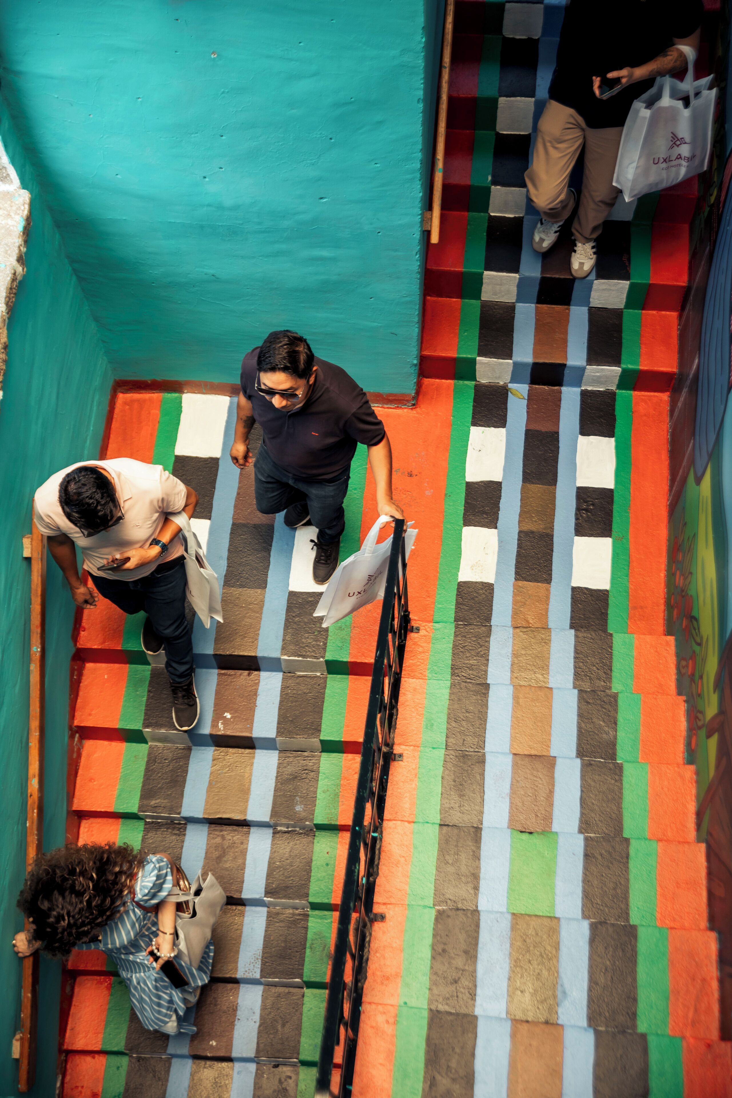 Uma escadaria com padrão xadrez, que conduz a uma porta com parede colorida.