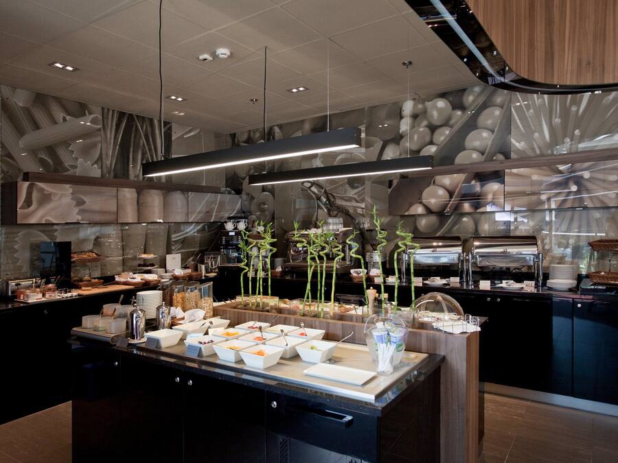 Um balcão de café da manhã moderno com diversos alimentos e um arranjo decorativo de plantas.