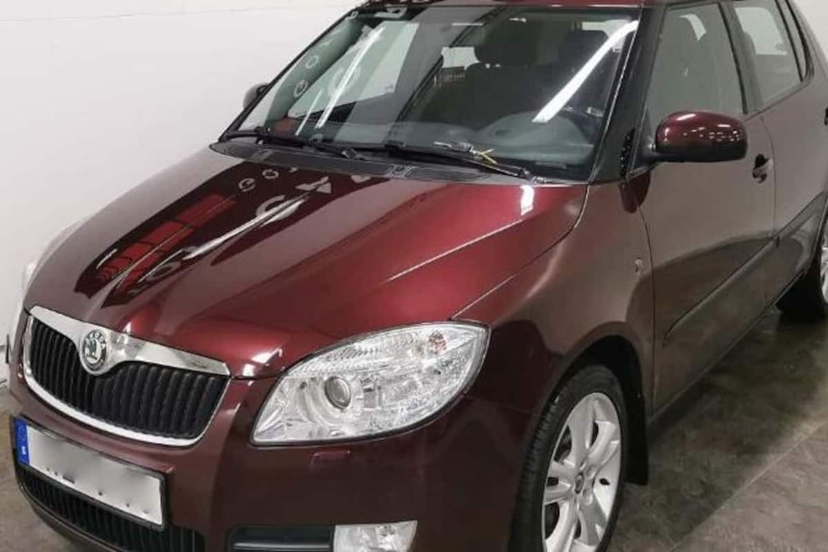 Um carro compacto vermelho-escuro estacionado em ambiente interno.