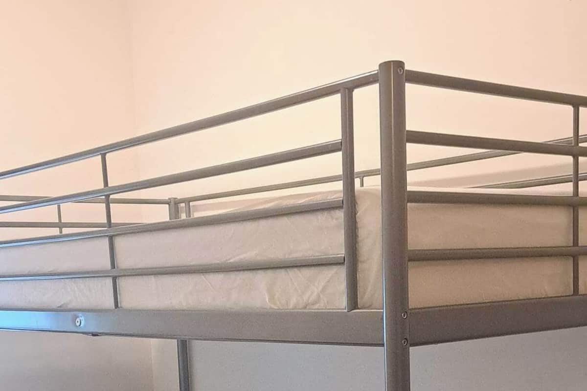 Uma cama beliche com grades de metal e um colchão.