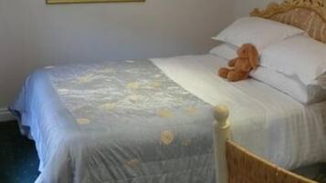 Cama com colcha azul, um ursinho de pelúcia e cabeceira de madeira.