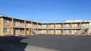Um motel de vários andares com pátio central, varandas e estacionamento.