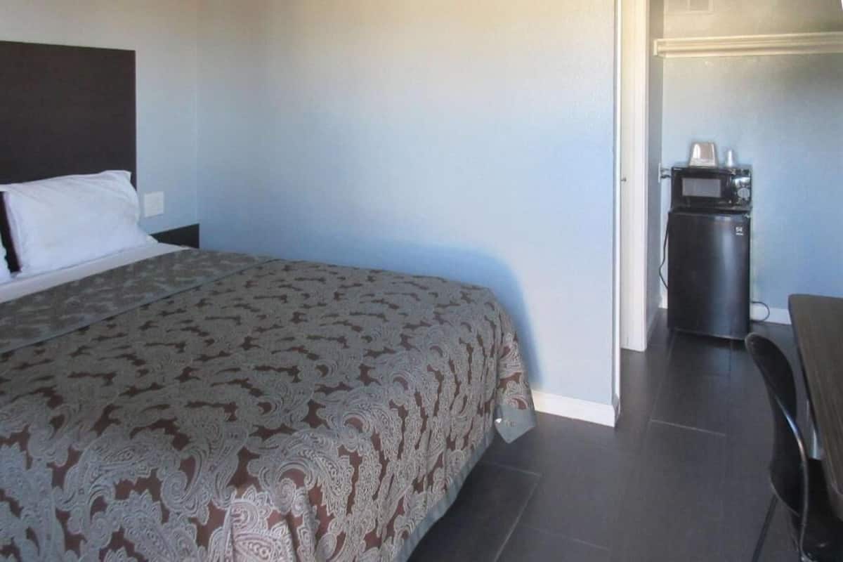 Quarto de hotel com uma cama, uma mesa de trabalho e uma máquina de café.