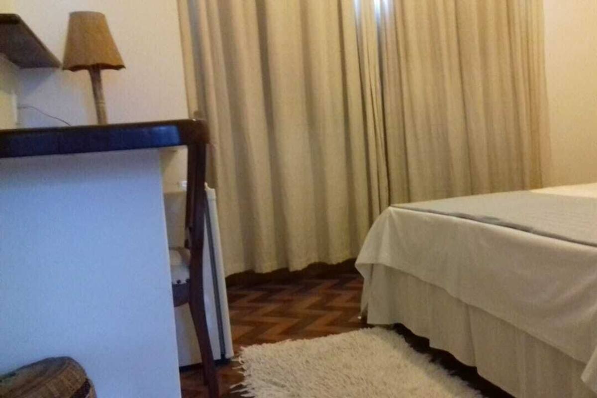 Quarto com cama, escrivaninha e abajur.