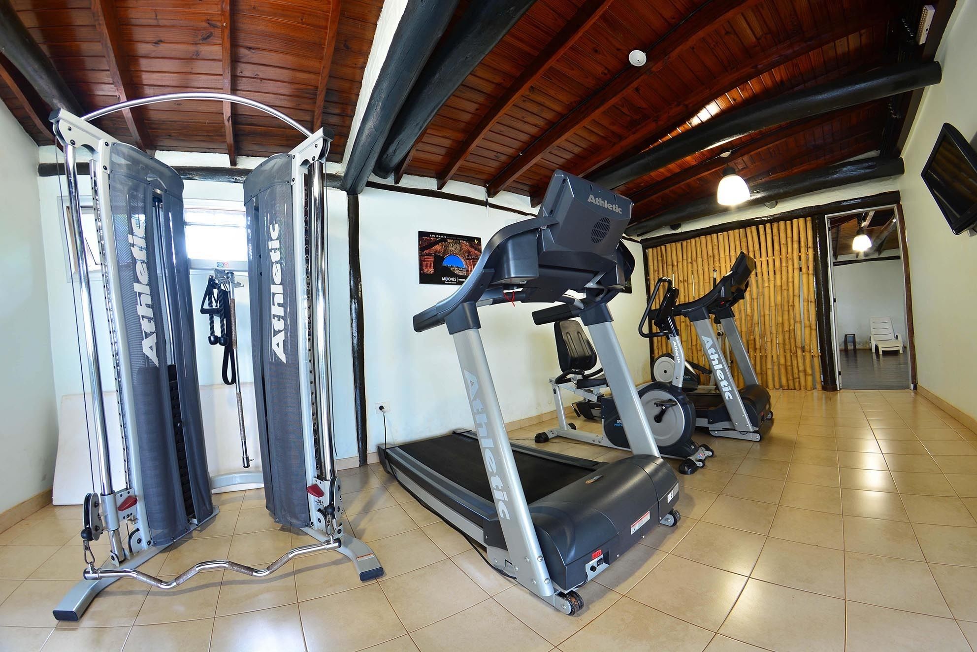 Academia com esteiras, aparelhos de musculação e espelho.