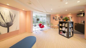Um interior moderno com uma mesa de recepção, uma estante de livros e uma área de estar com um banco azul.